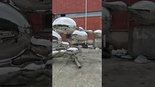 This mirrored stainless steel sculpture is composed of smooth, rounded spheres of varying sizes